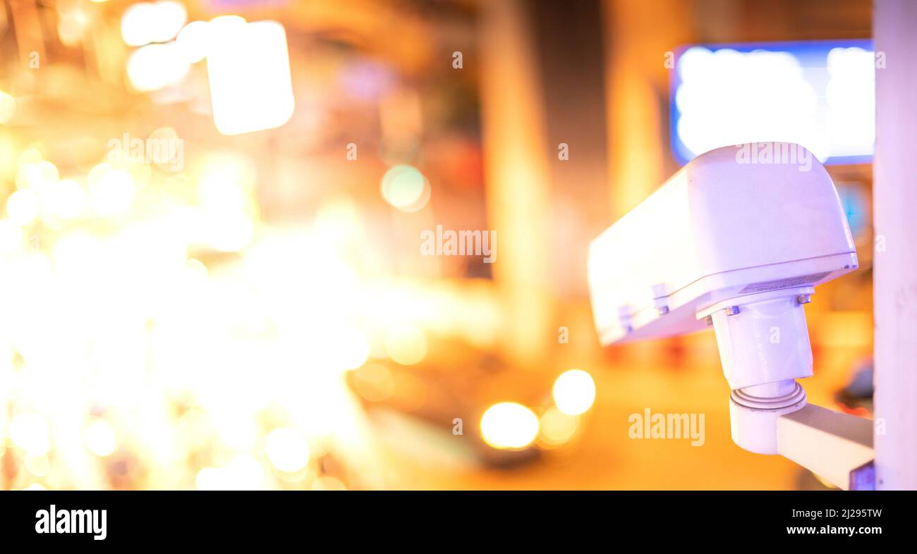 Modern CCTV camera on a wall. A blurred night cityscape background. For ...