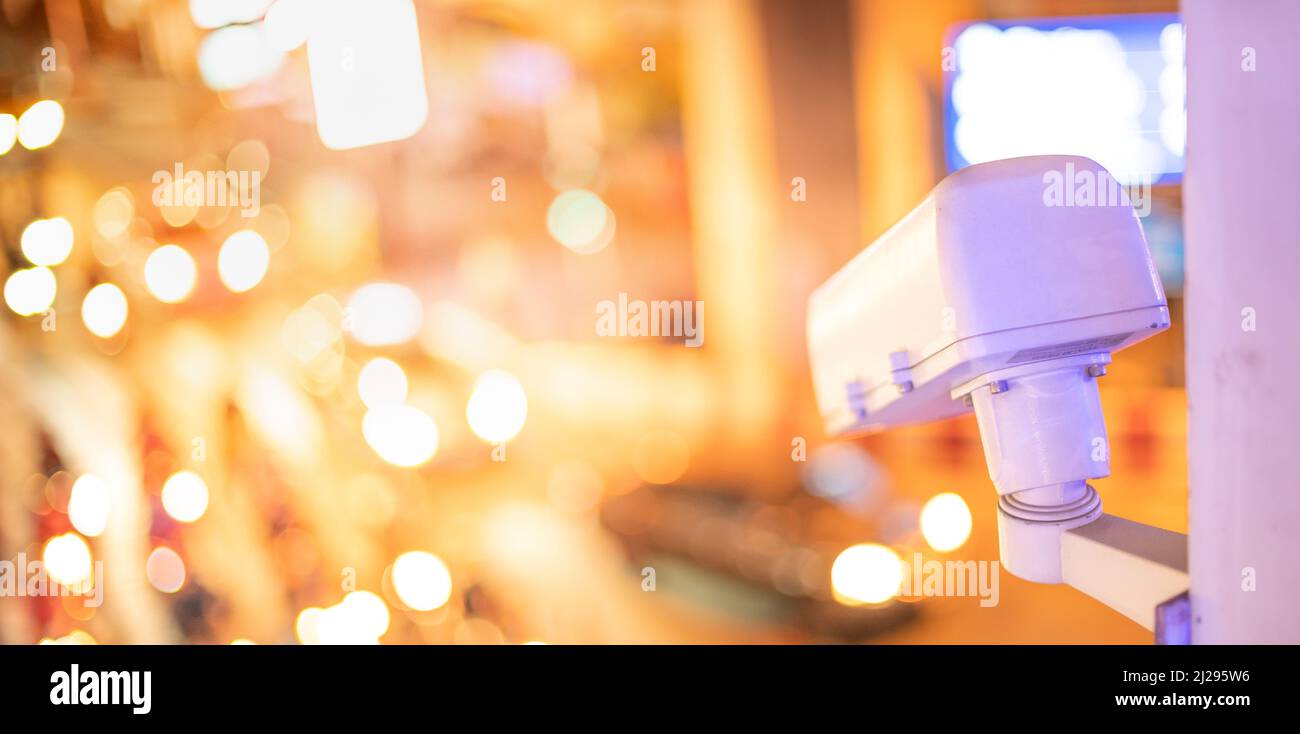Modern CCTV camera on a wall. A blurred night cityscape background. For ...