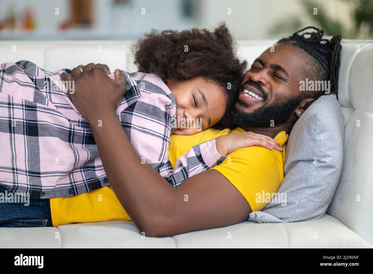 Happy man hugging daughter lying on sofa Stock Photo - Alamy