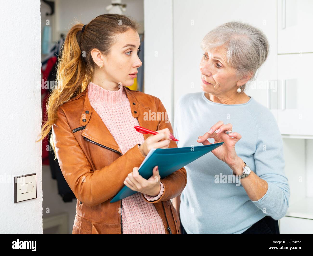 Senior and younger women filling rent contract Stock Photo - Alamy
