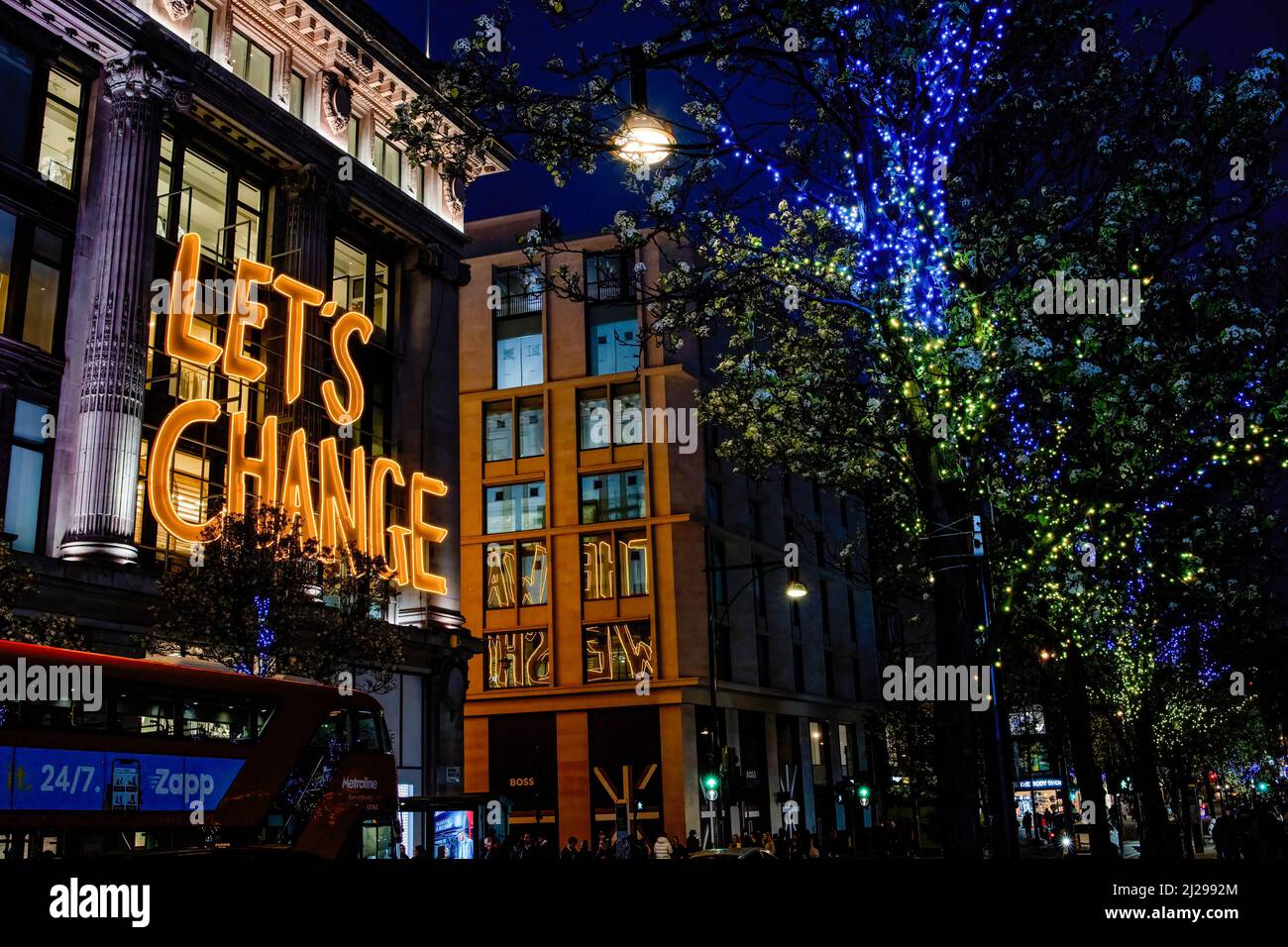 A view of a lit sign "Let's change" on the wall of Selfridges on Bond ...