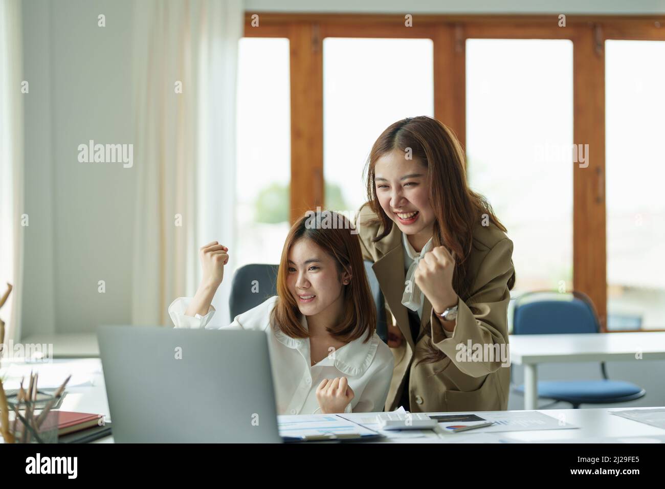 Happy young business asian team looking at laptop screen, celebrating ...