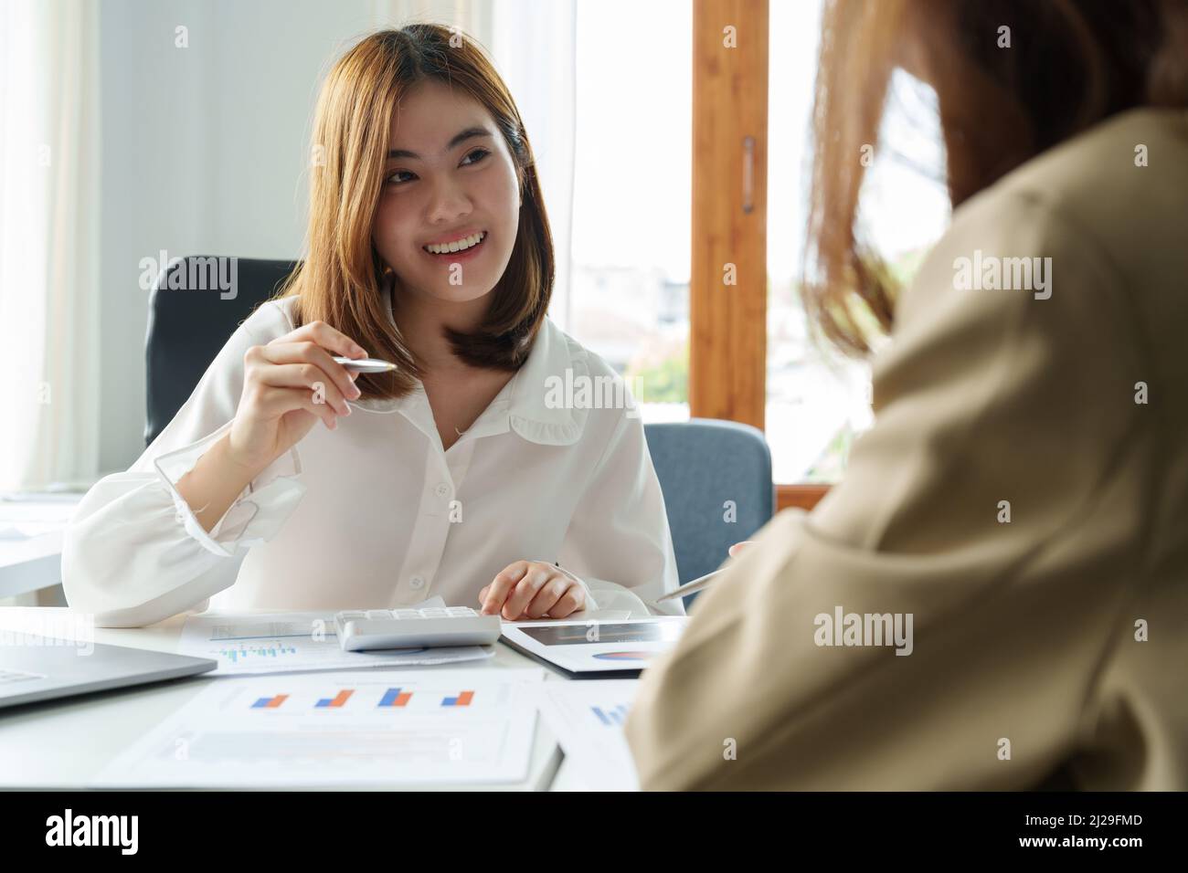 Two young beautiful asian business woman in the conversation ...