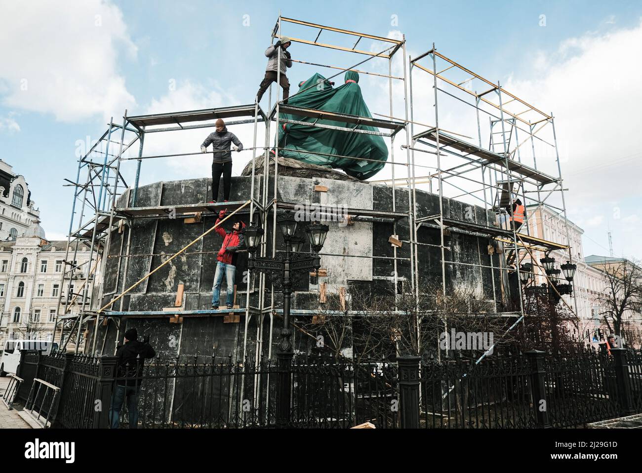 Volunteers and residents place protective barriers around a monument to ...