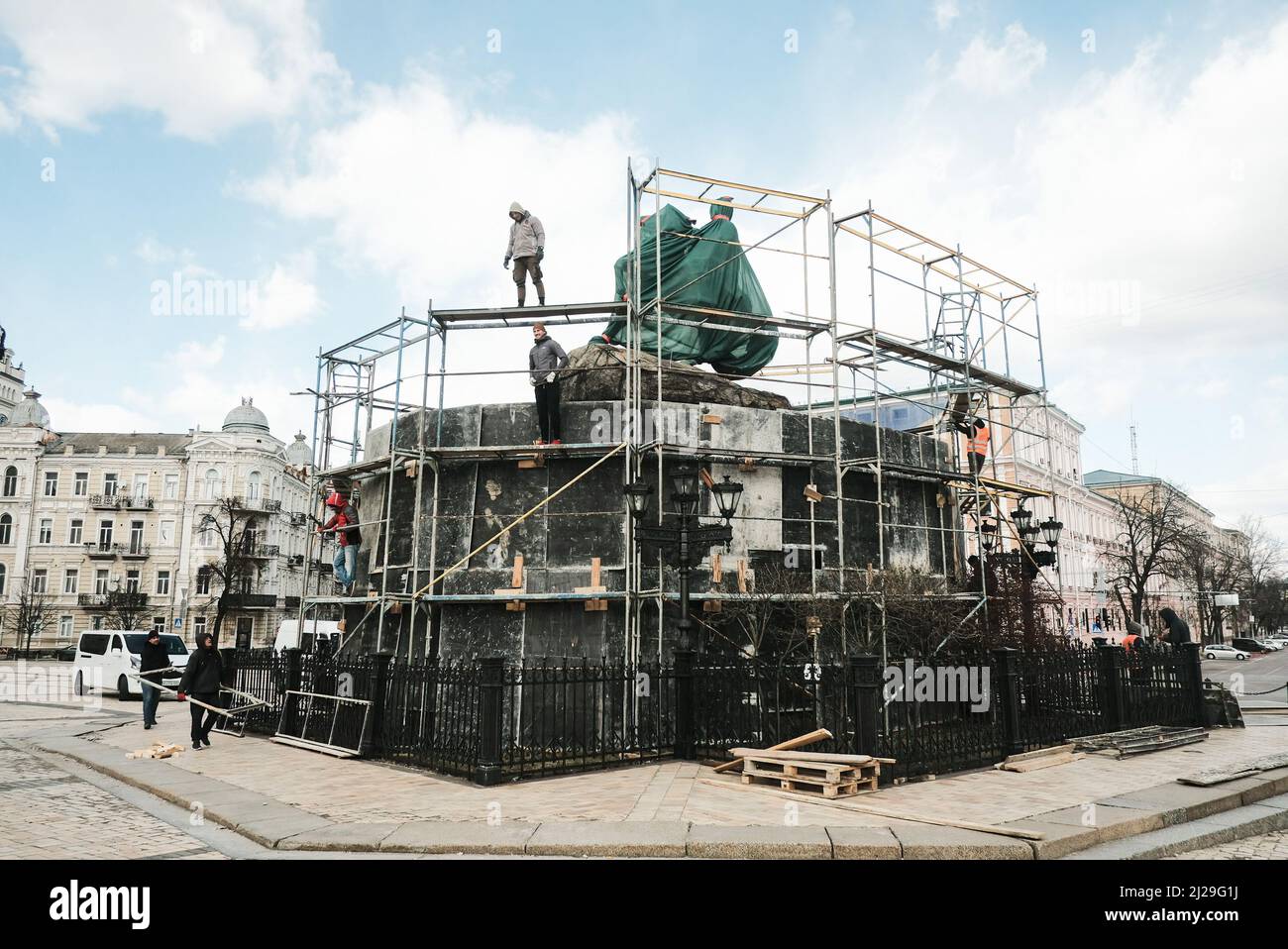 Volunteers and residents place protective barriers around a monument to ...