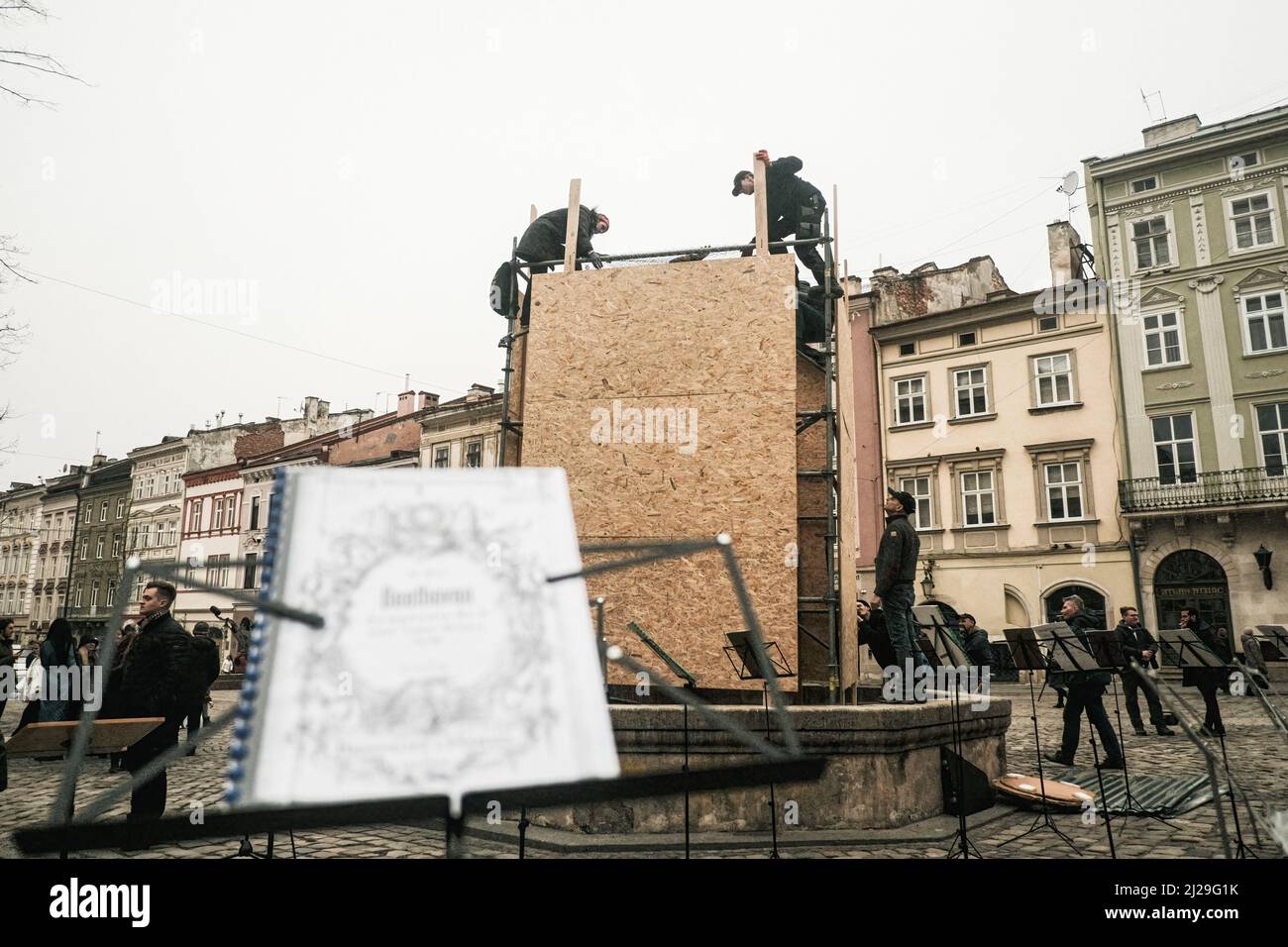 Volunteers and residents place protective barriers around a monument to ...