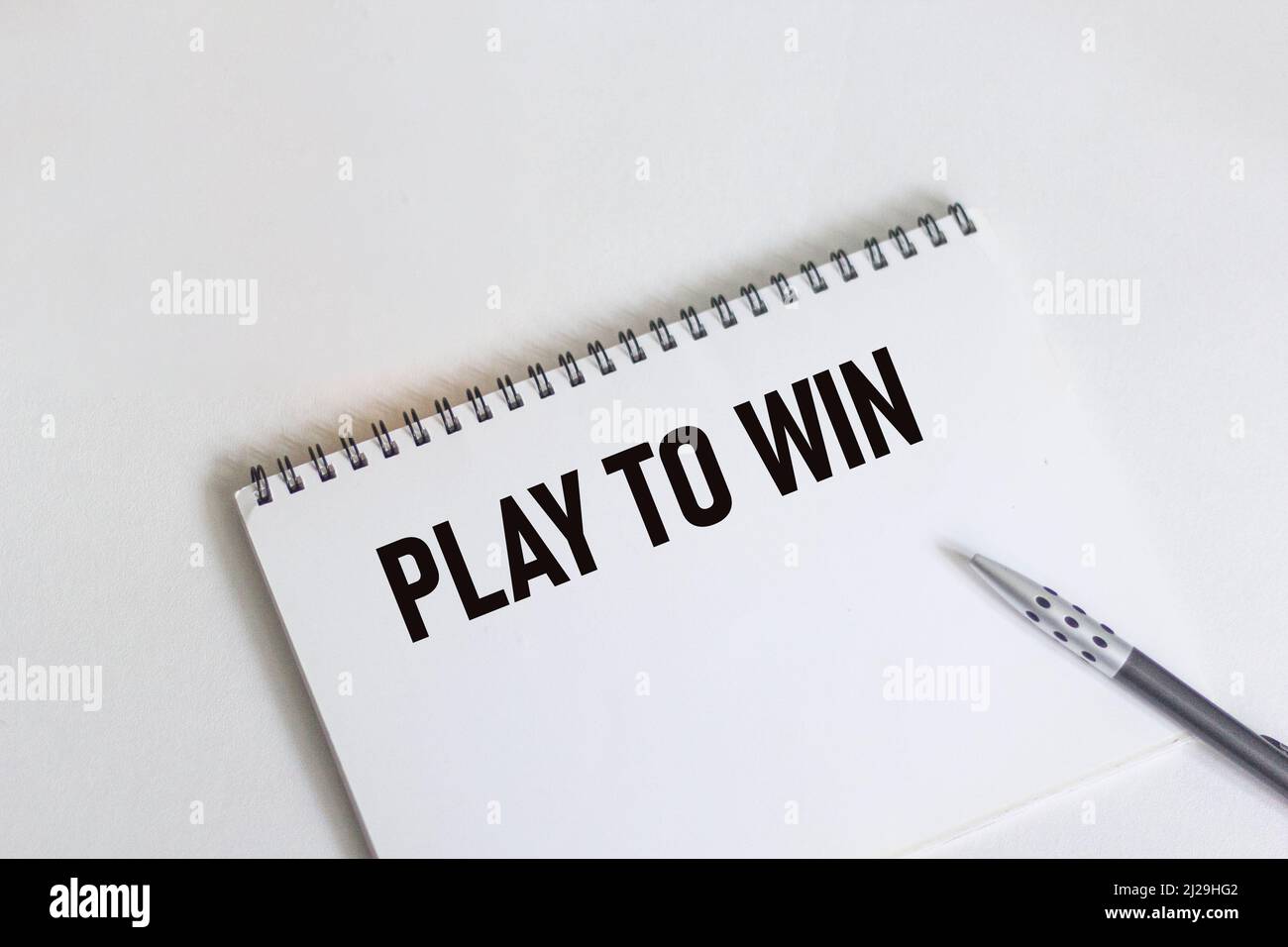 Play to Win written on a notebook with a pen on a white background ...