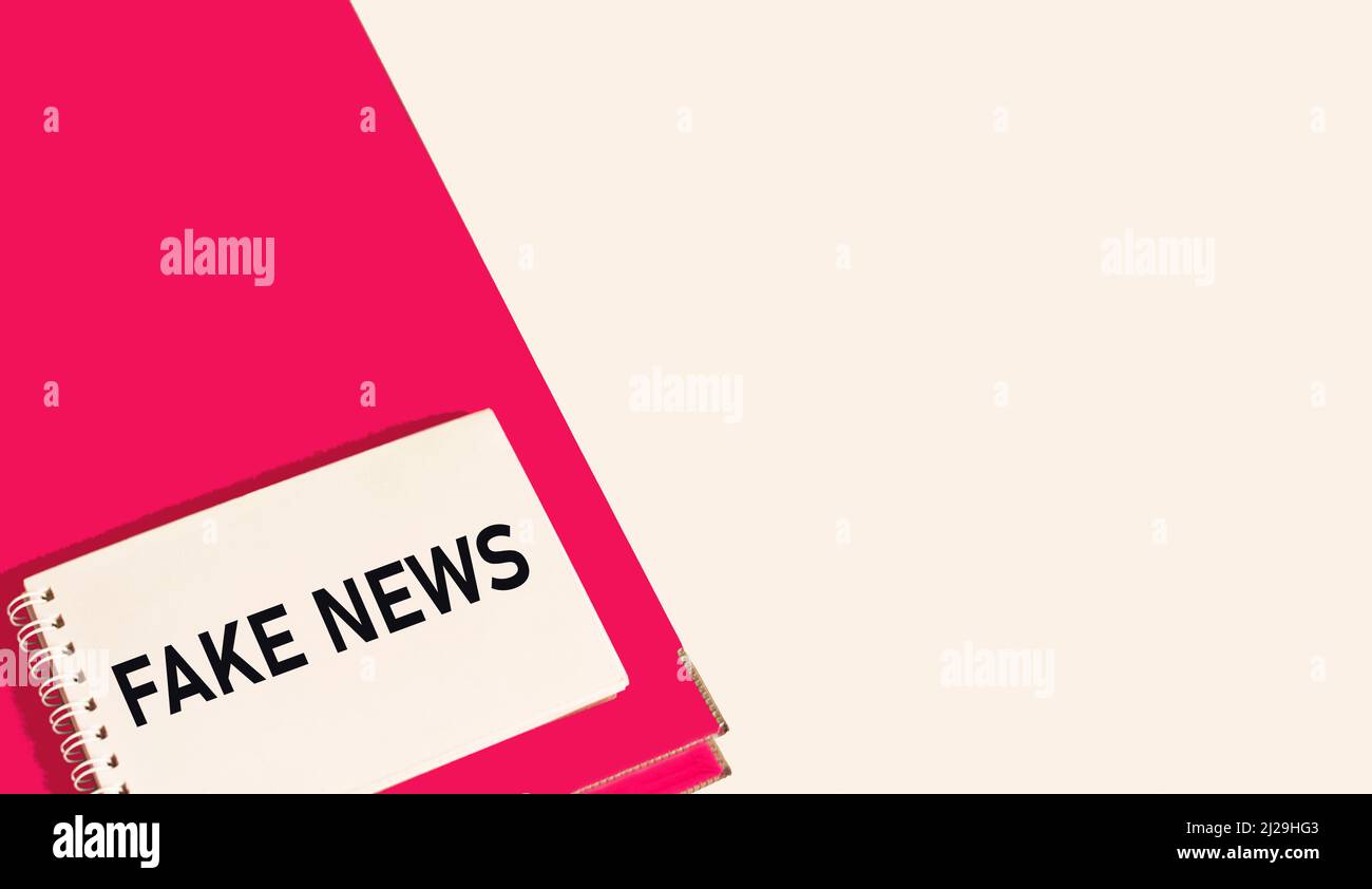 Fake news text on notepad with pink folder and white background .Copy ...