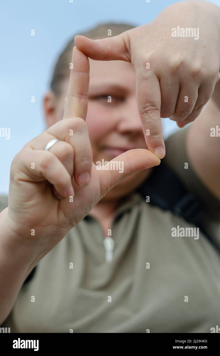 An adult woman makes a vertical rectangular frame shape with her hands ...