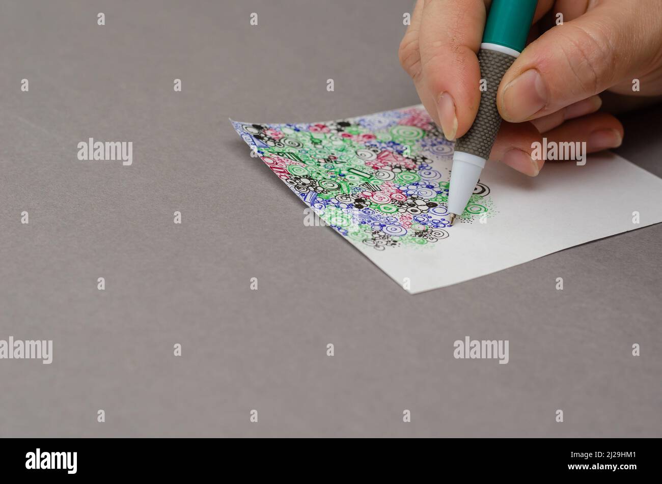 A woman's manicure-less hand draws an abstract drawing with a pen. A ...