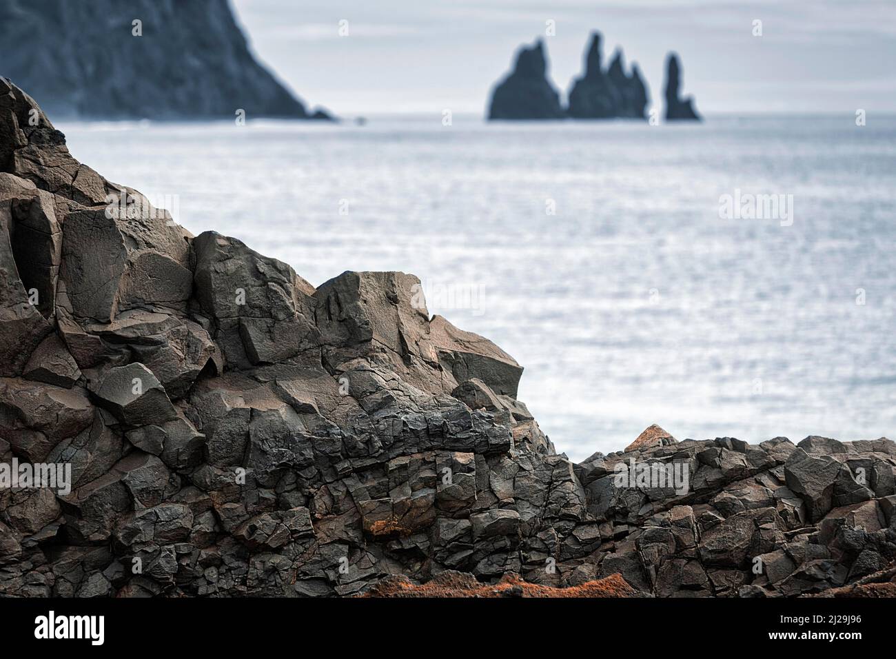 Basalt rocks with a view of the sea and the rock needles Reynisdrangar ...
