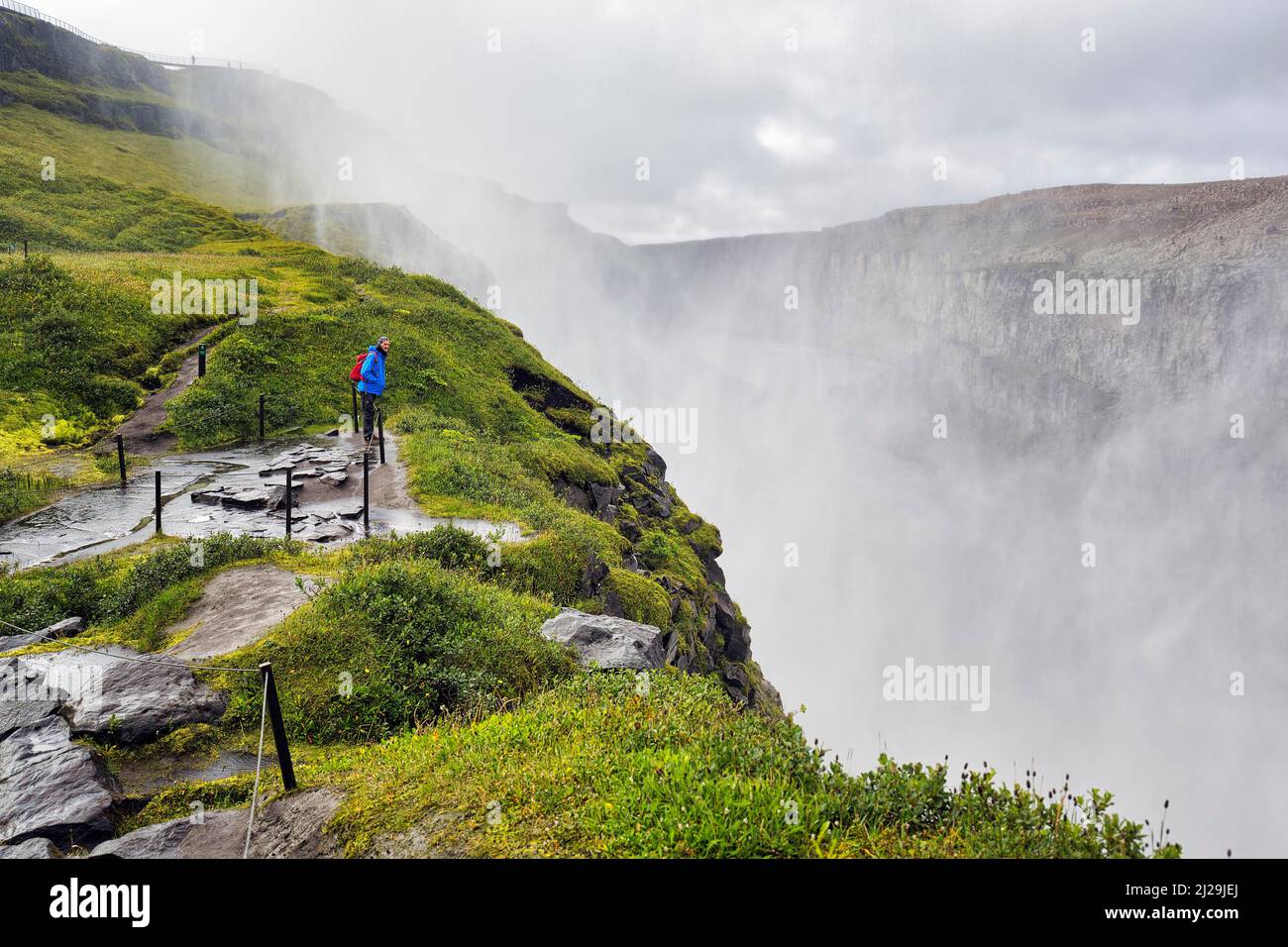 Hiker at the edge of Dettifoss, tourist looking down into the gorge ...