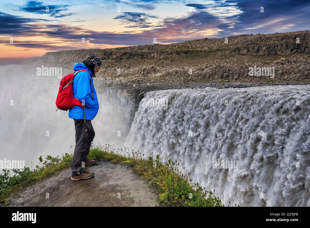 Hiker at the edge of Dettifoss, tourist looking down into the gorge ...