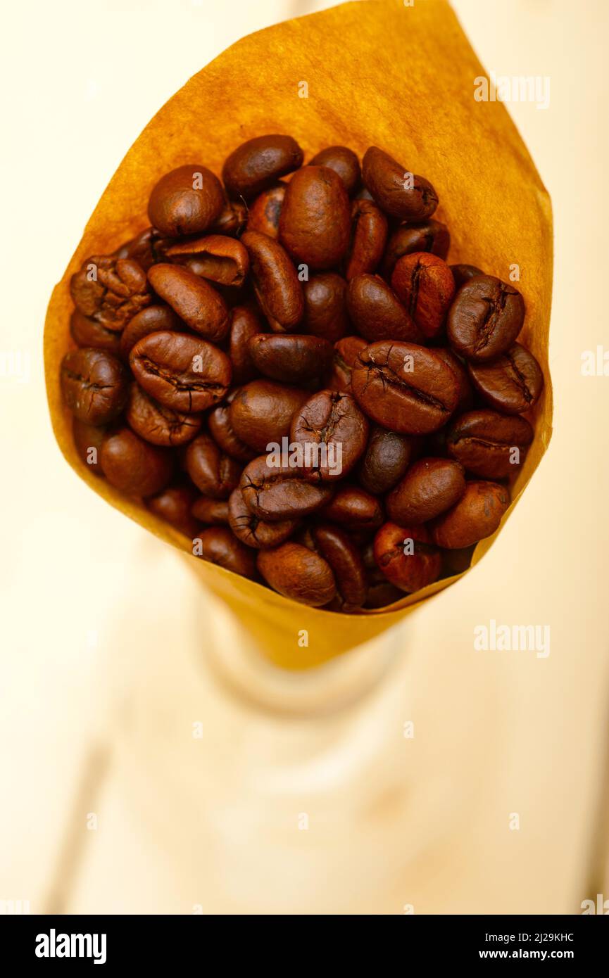 Espresso coffee beans on a paper cone cornucopia over white background ...