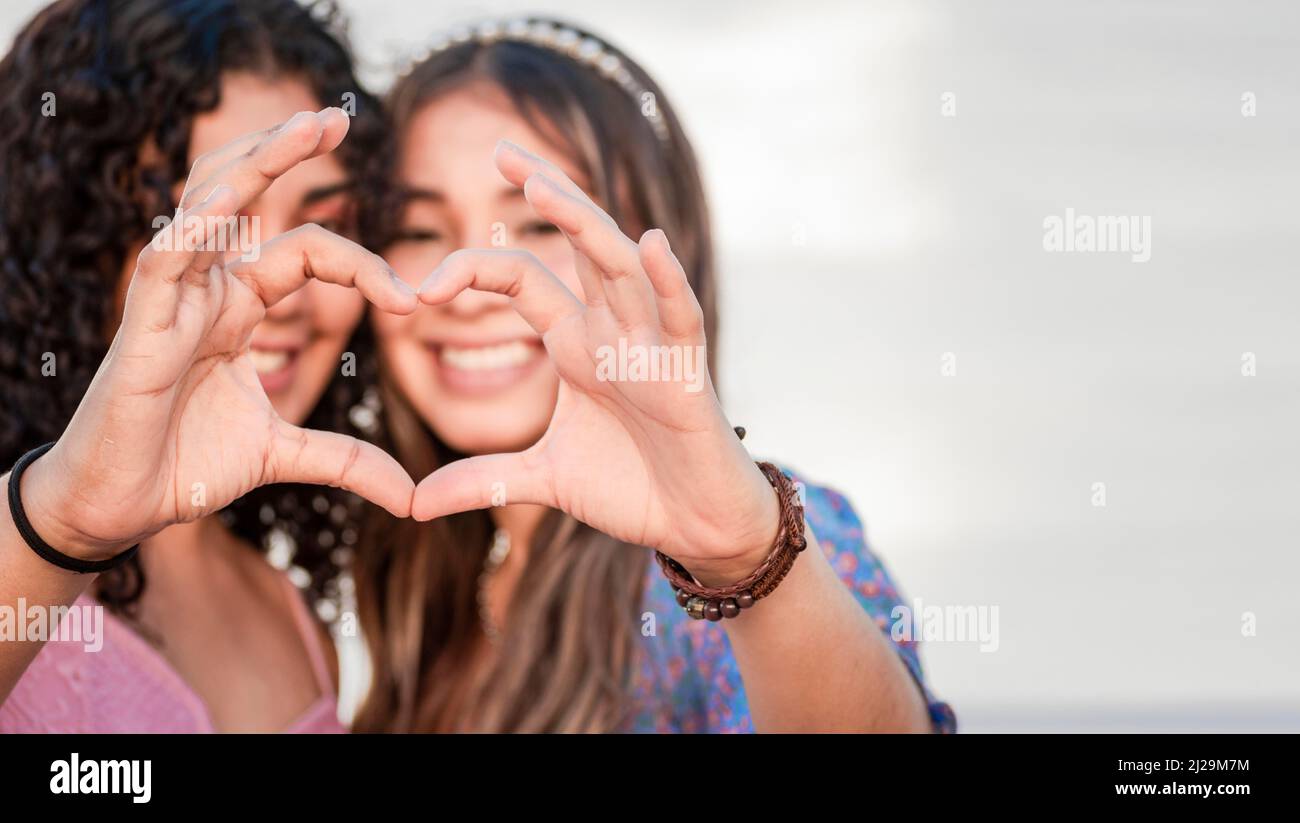 Close up of two girls forming heart with hands, two girls friends ...