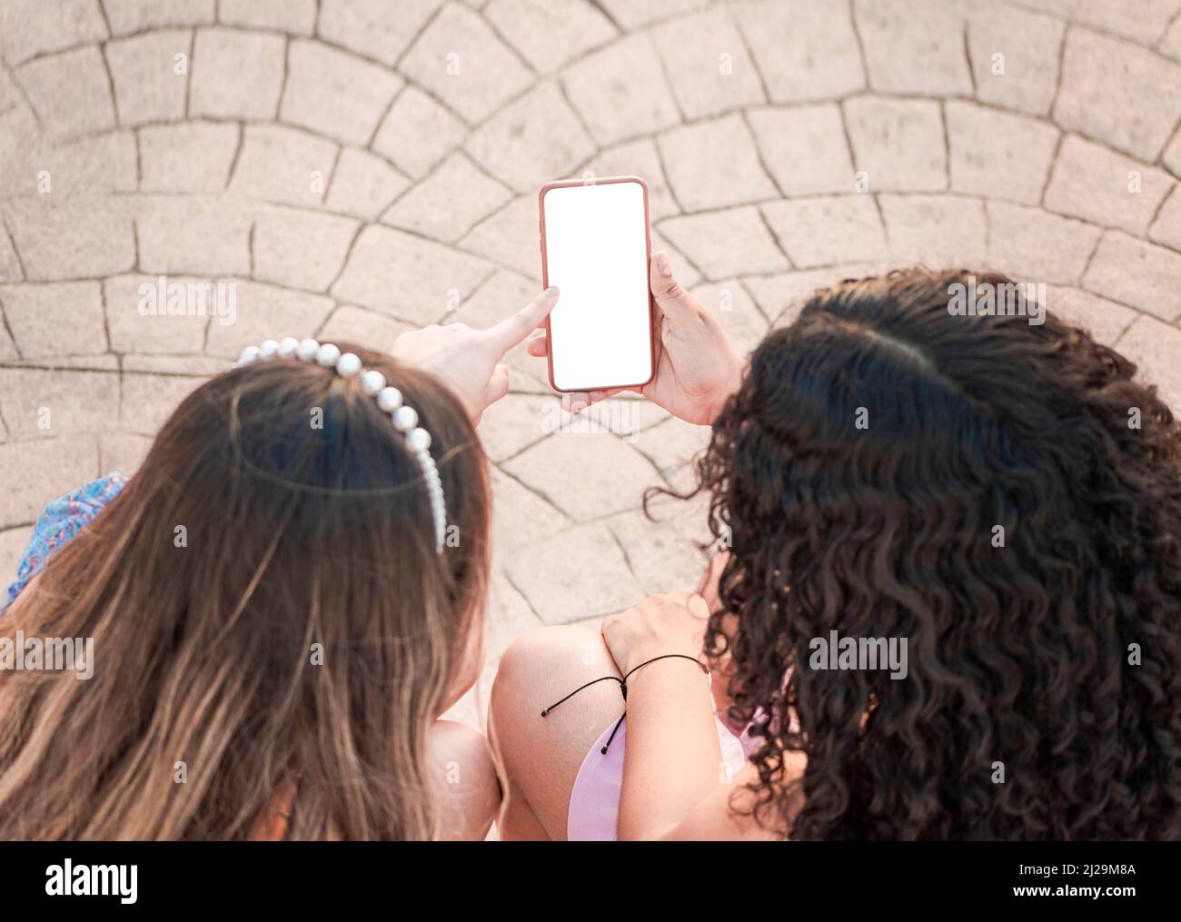 Girl friend showing her cell phone screen, two girls pointing at her ...