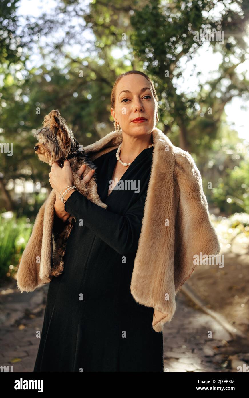 Middle aged posh woman looking at the camera while holding her puppy ...