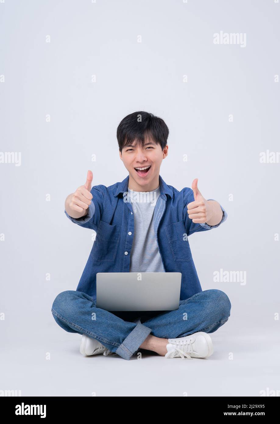 Young Asian man sitting and using laptop on white background Stock ...