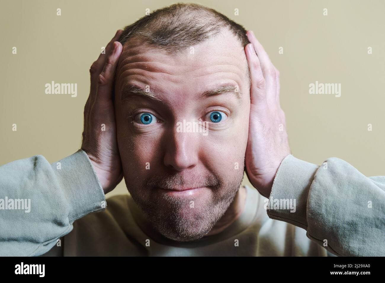 The man covers his ears with his hands. Portrait of a young man making ...
