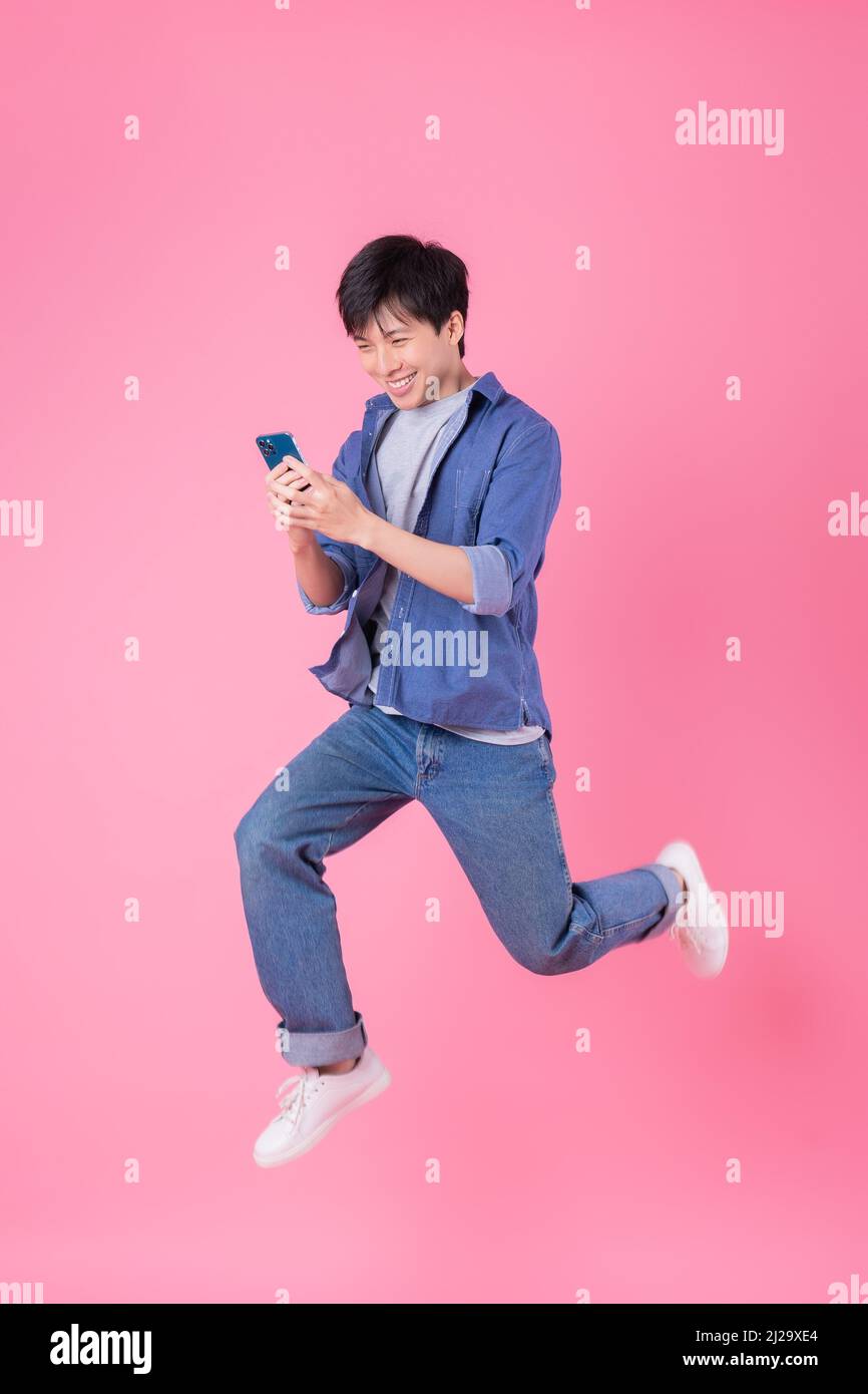 Young Asian man jumping on blue background Stock Photo - Alamy