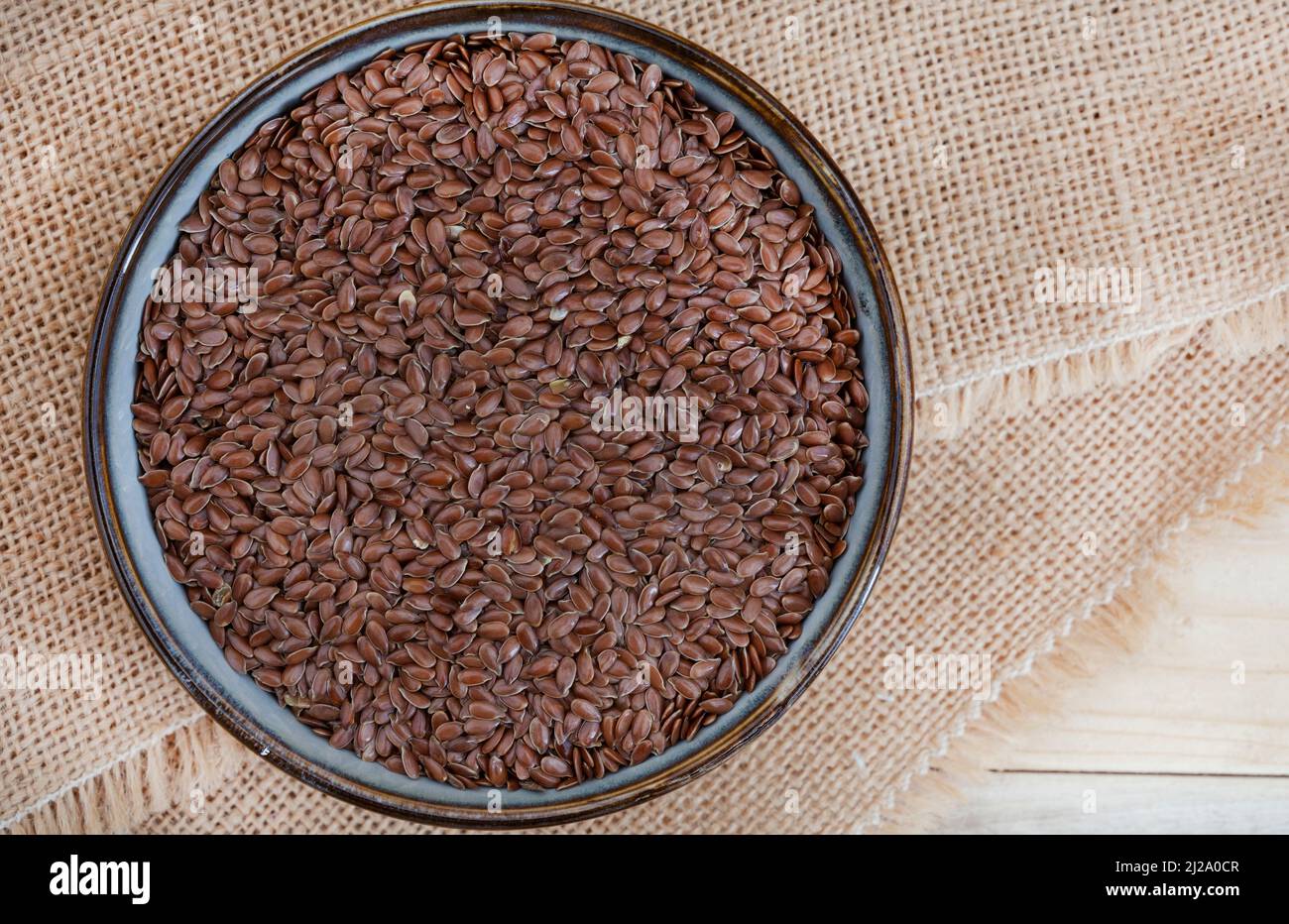 Bowl of whole linseed on hessian and rustic table with copy space Stock Photo - Alamy