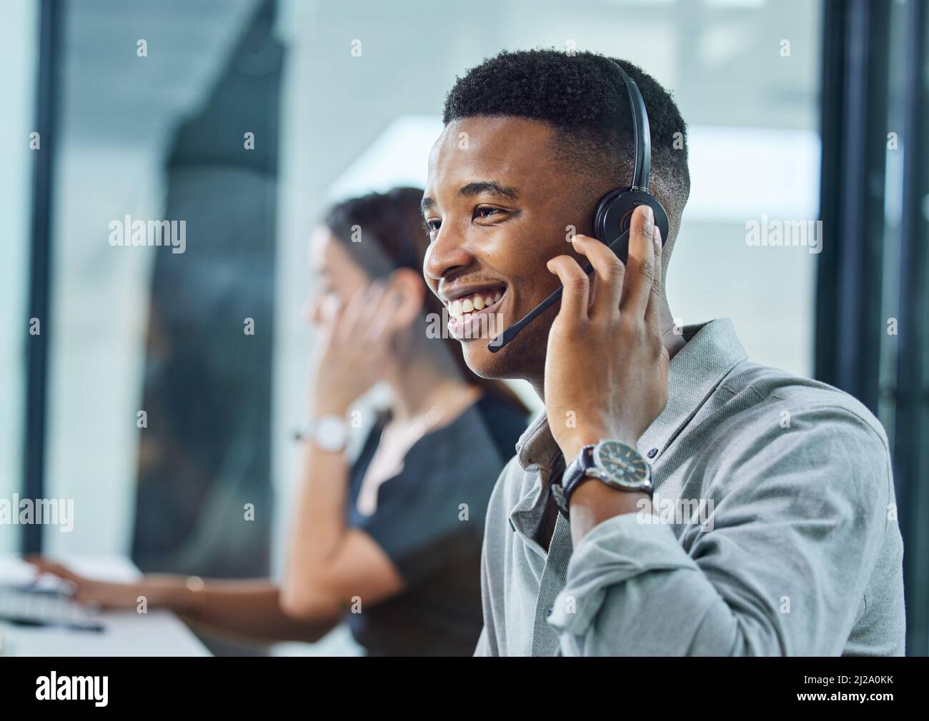 Im here to help you. Shot of a young call centre agent on a call in an ...