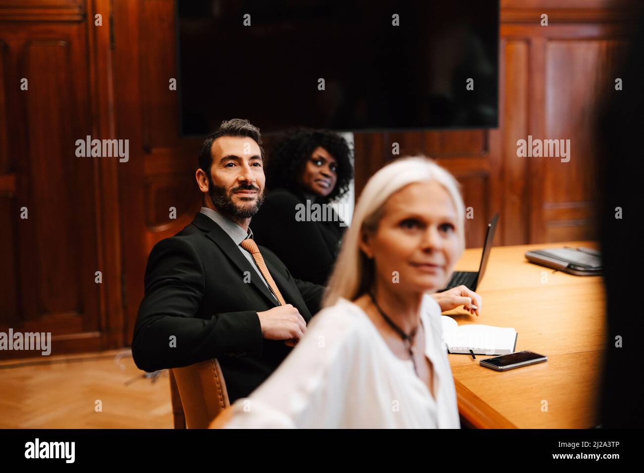 Multiracial colleagues sitting at conference table in board room during ...