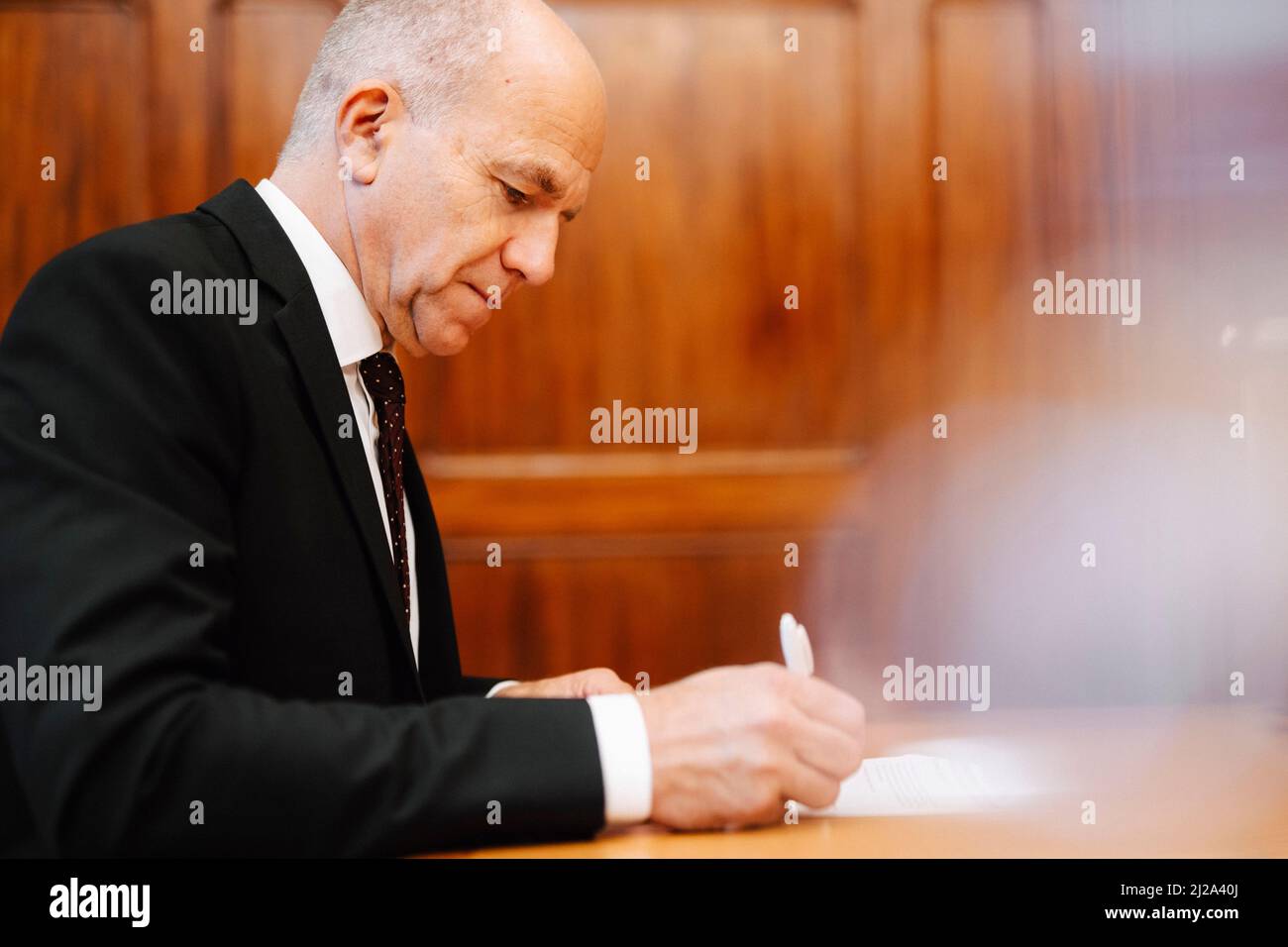 Side view of senior businessman signing contract document in board room ...