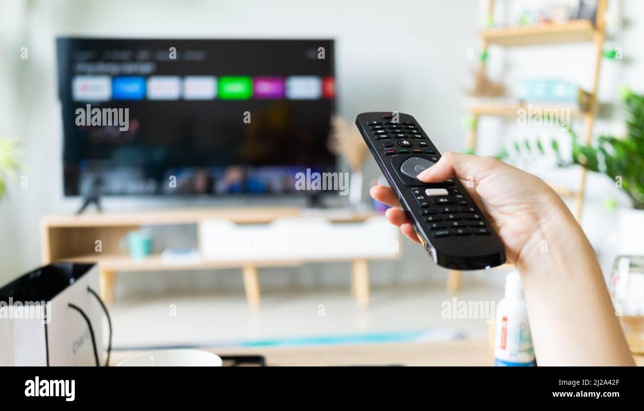 Asian woman holding tv remote in hand to change channel Stock Photo - Alamy