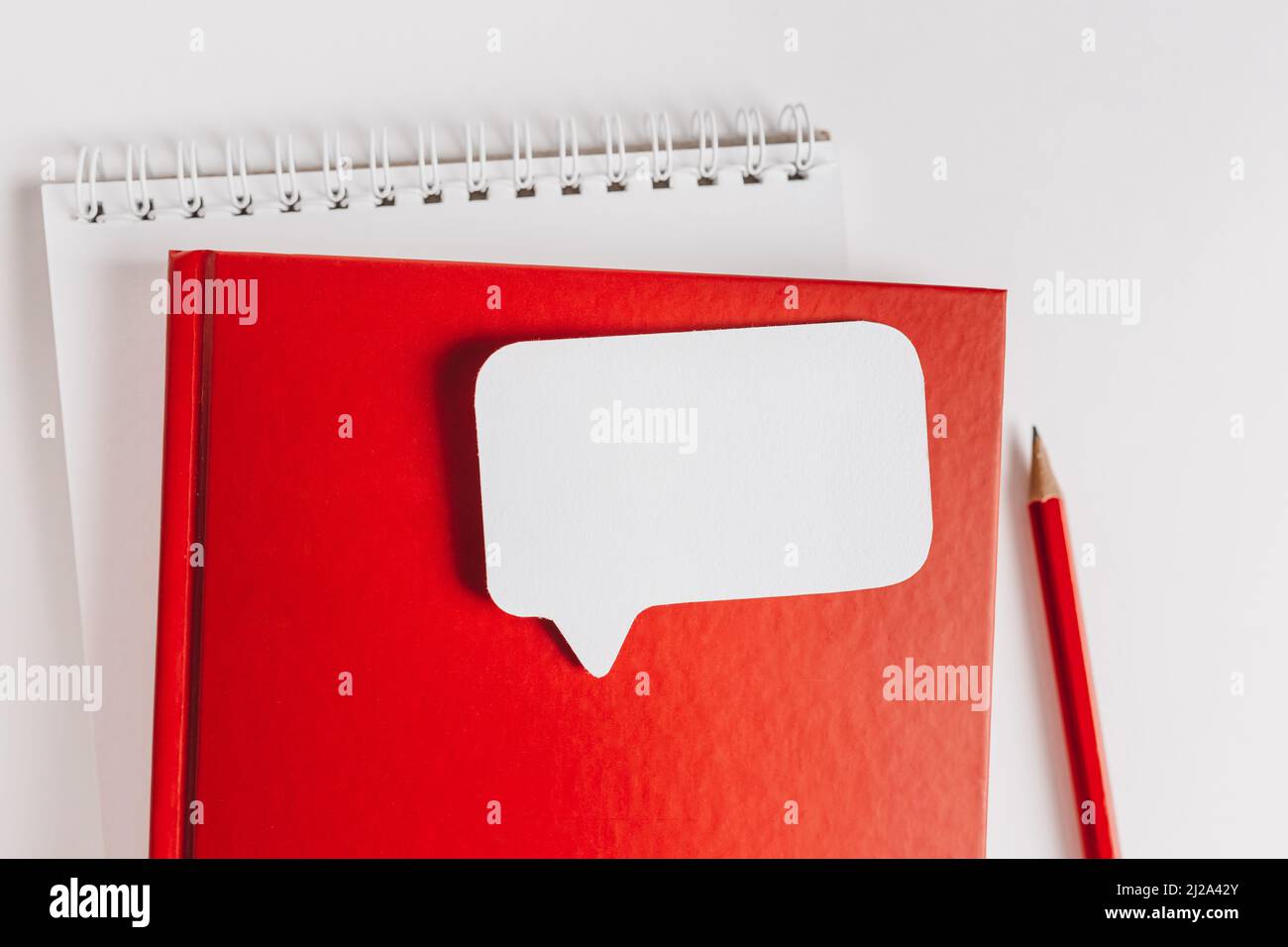 Red notepad and white sticker on the desk. Mock up in copy space office ...
