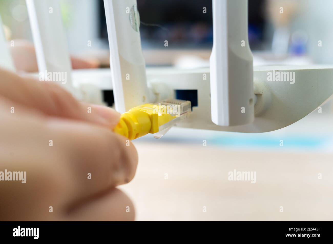 Asian woman plugging network cable into router Stock Photo - Alamy
