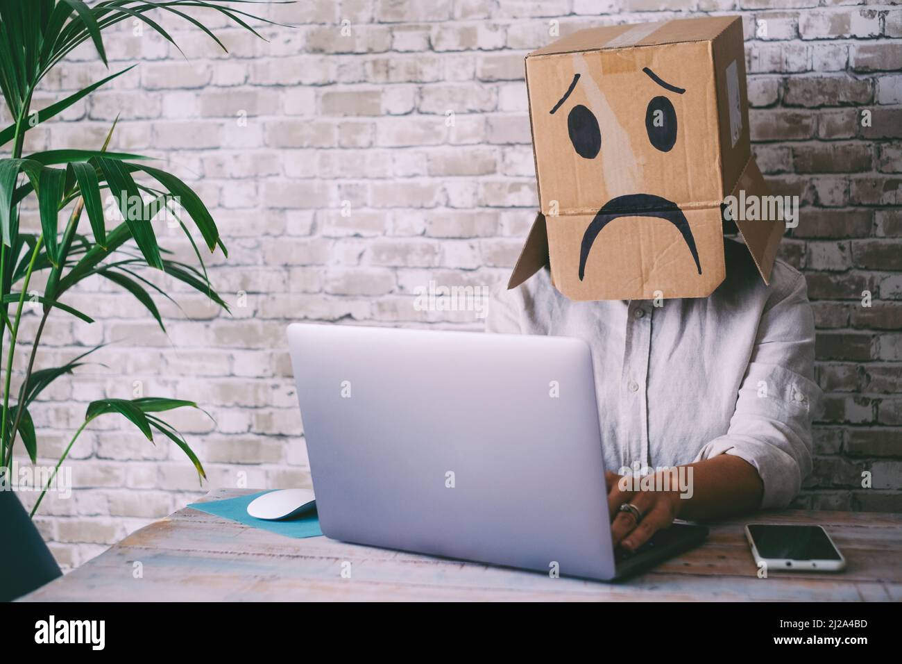 Sad people working on laptop wearing paper box on his head. Concept of ...