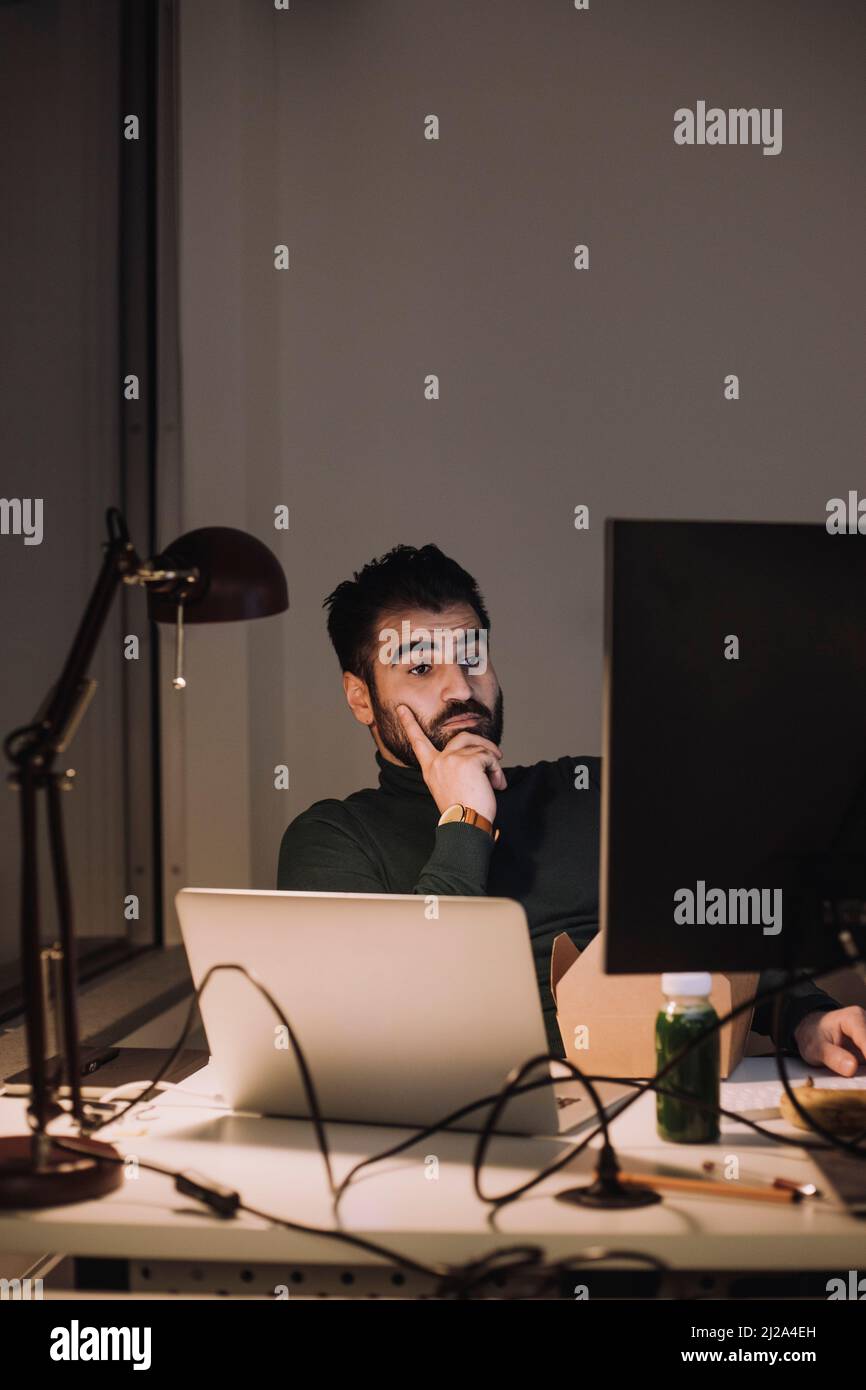 Businessman using computer while working overtime at work place Stock ...