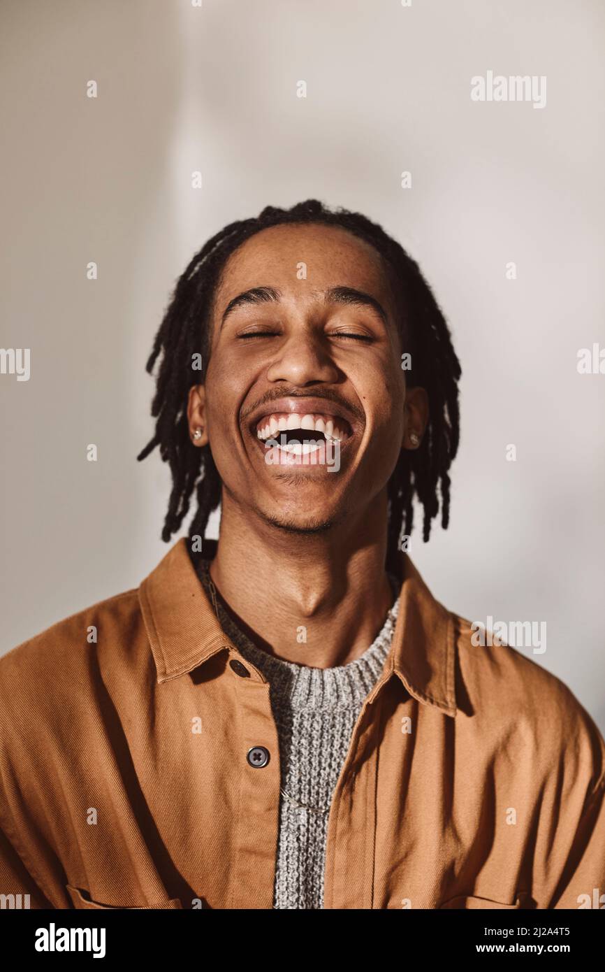 Young man laughing against white background Stock Photo - Alamy