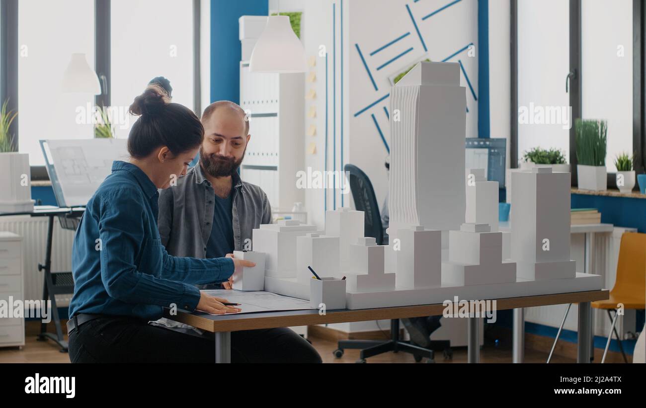 People working together to design blueprints plan with building model ...