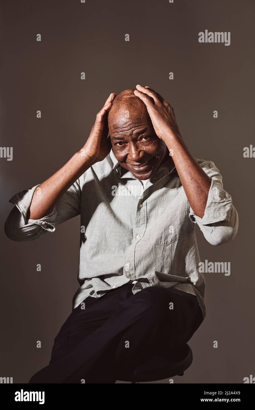 Smiling man touching head against white background Stock Photo - Alamy
