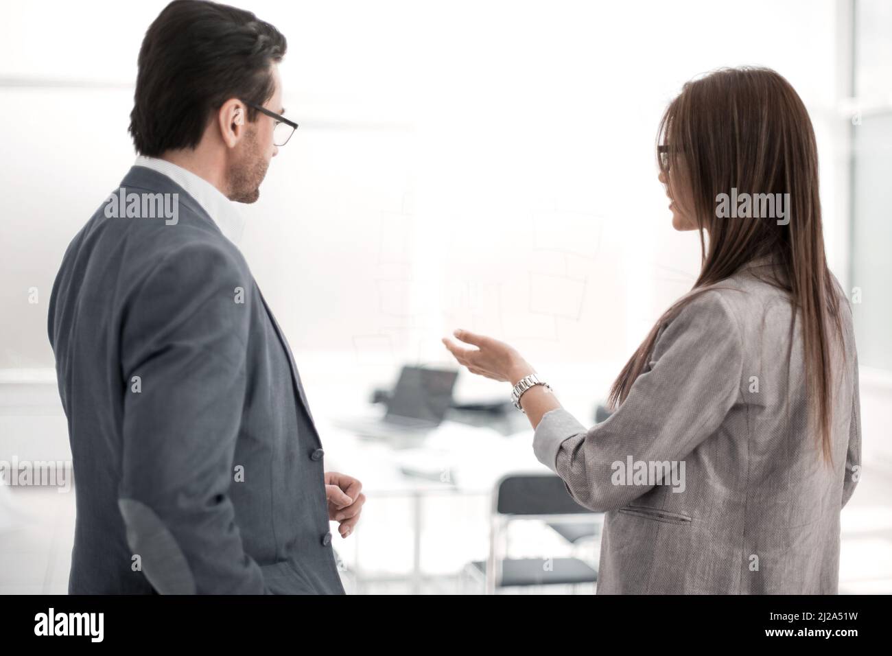 rear view.businessman and businesswoman talking standing in the new ...