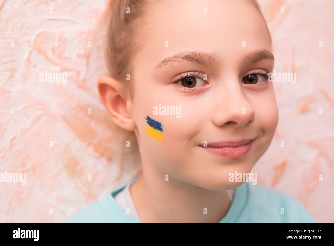 face of a frightened girl, a painted heart on the cheek in yellow-blue ...