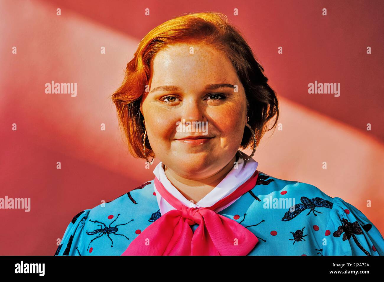 smiling young woman portrait in studio over pink background redhead ...