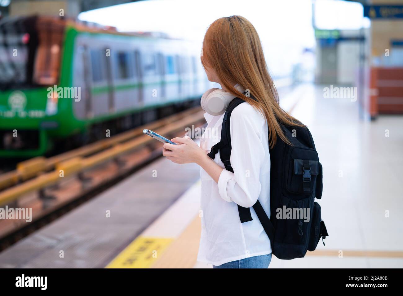 Young Asian girl waiting for the train at the station Stock Photo - Alamy