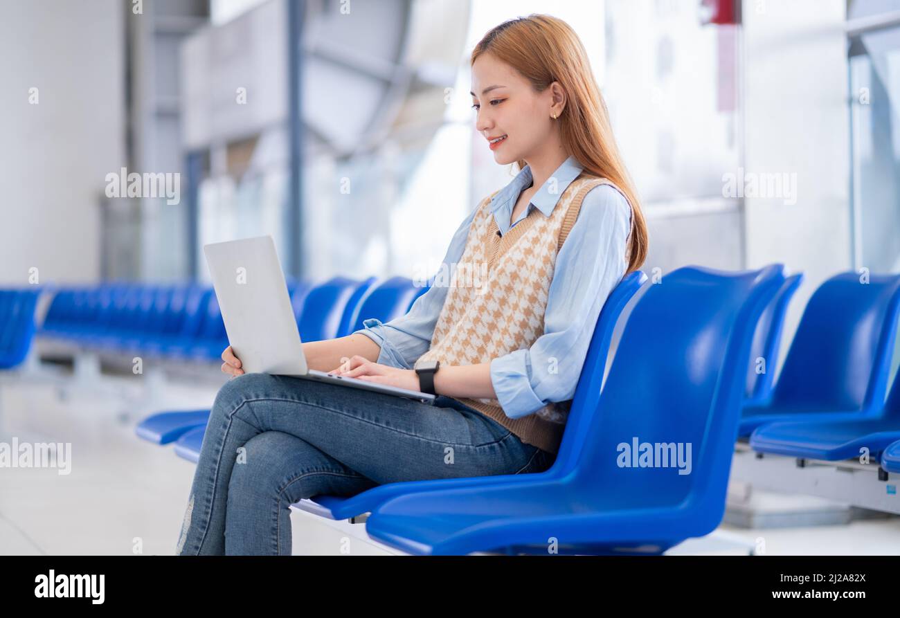 Young Asian woman working while waiting for the train at the train ...
