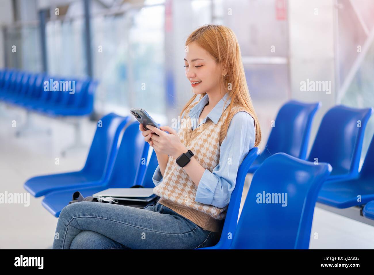 Young Asian woman working while waiting for the train at the train ...
