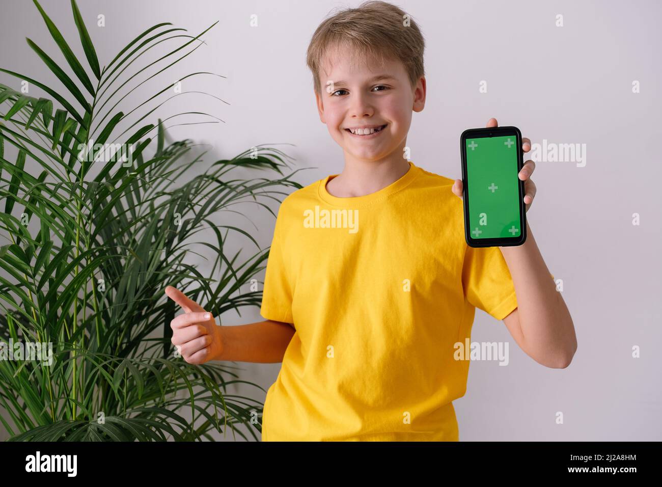 Happy Blond Schoolboy Pointing At Smartphone With Blank Screen In His ...