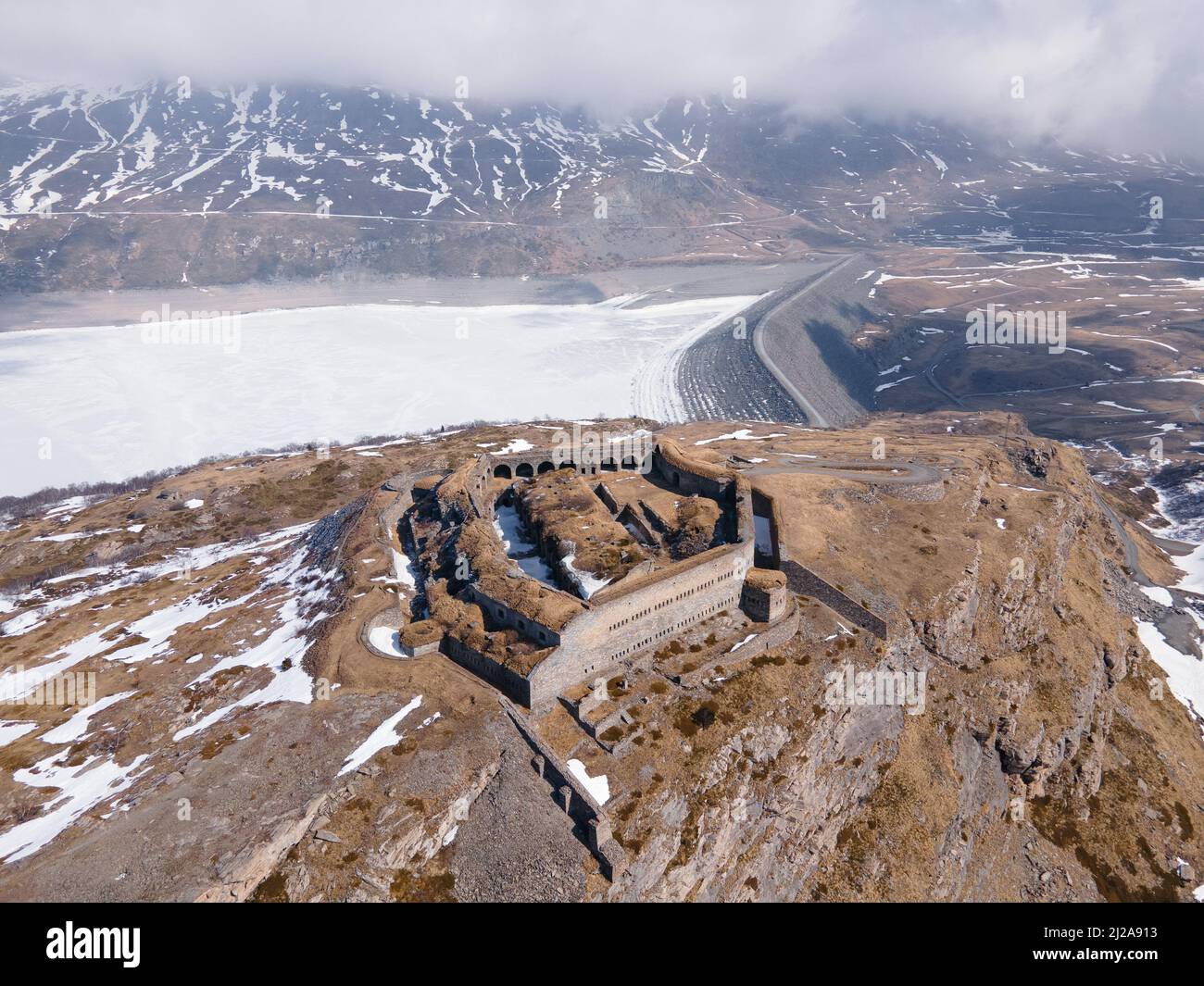 Aerial view of ancient fort ruins in the mountains next to frozen lake ...