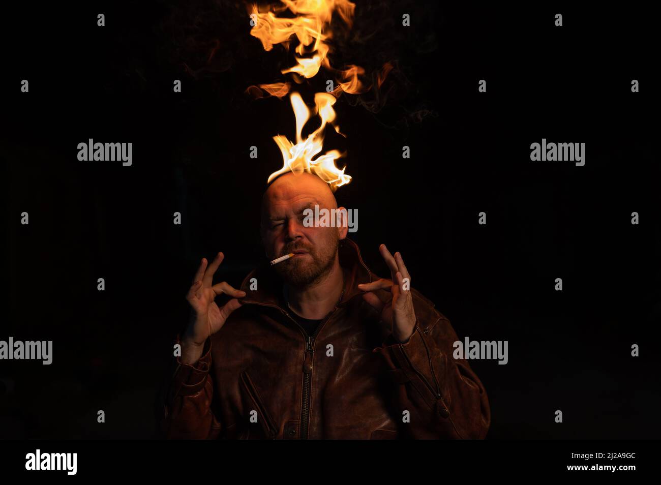 Bald man in a leather jacket with a burning head on a dark background ...