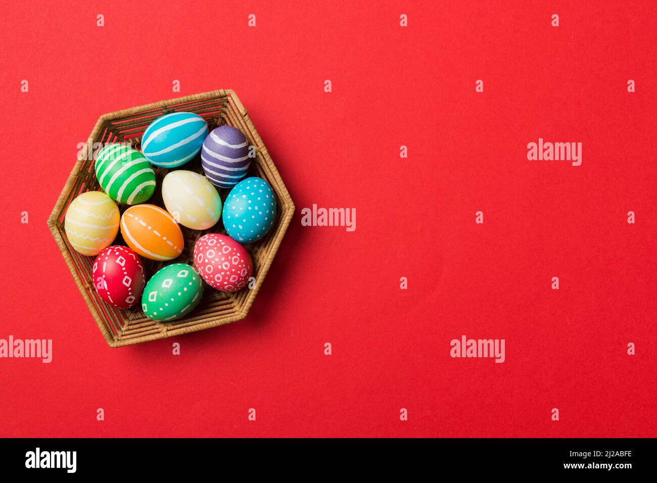Multi colors Easter eggs in the woven basket on colored background ...
