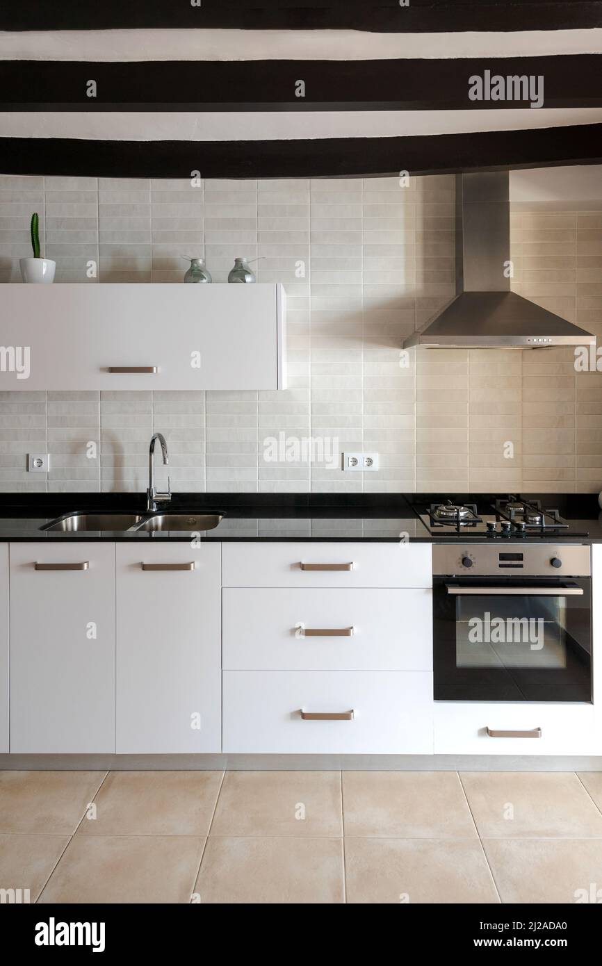White kitchen with natural light. White furniture with black marble ...