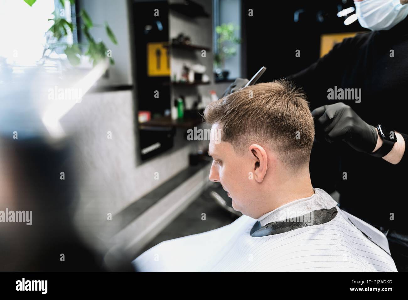 Visit to barbershop. Stylish man makes fashionable haircut. Barber ...