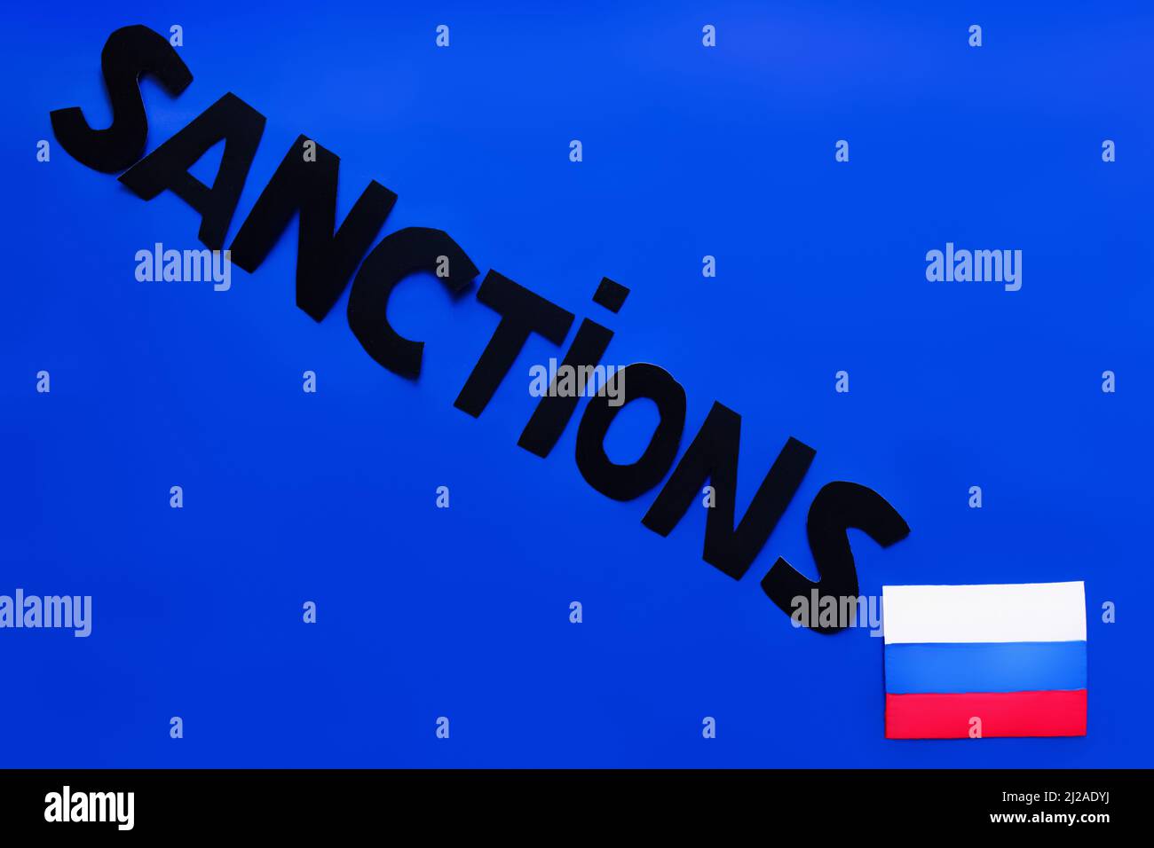 Top view of sanctions lettering and russian flag on blue background ...