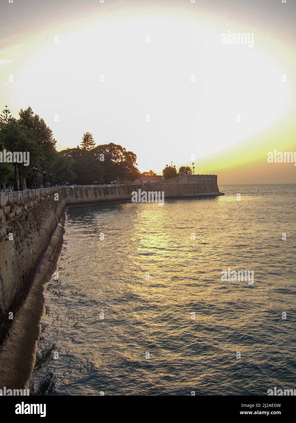The harbor coast with the great harbor wall of Cadiz at sunset ...